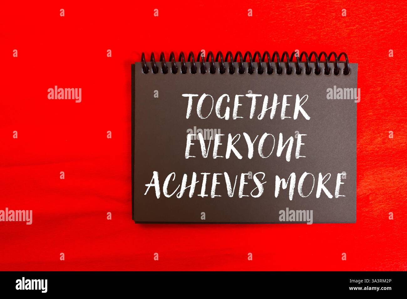Together everyone achieves more message written on black notebook page ...