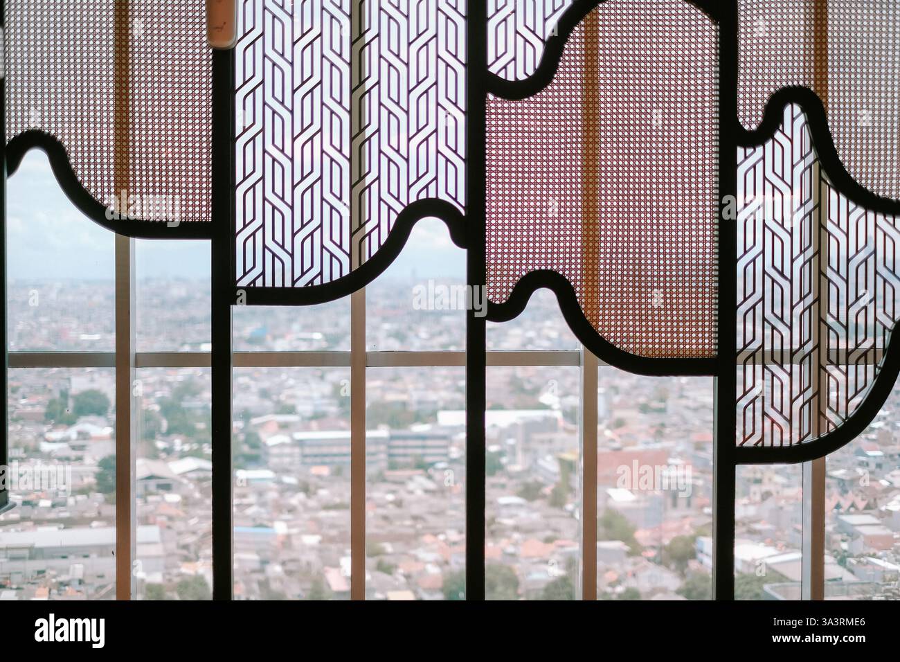 A detailed view through a decorative screen reveals a cityscape. The ...