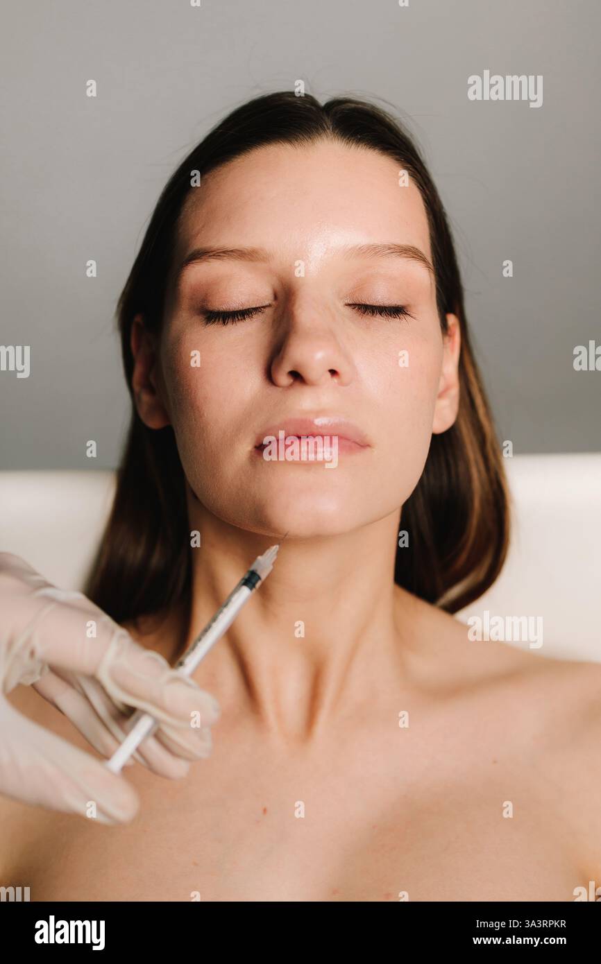 Cosmetologist making filler injection in female chin. Improving the ...