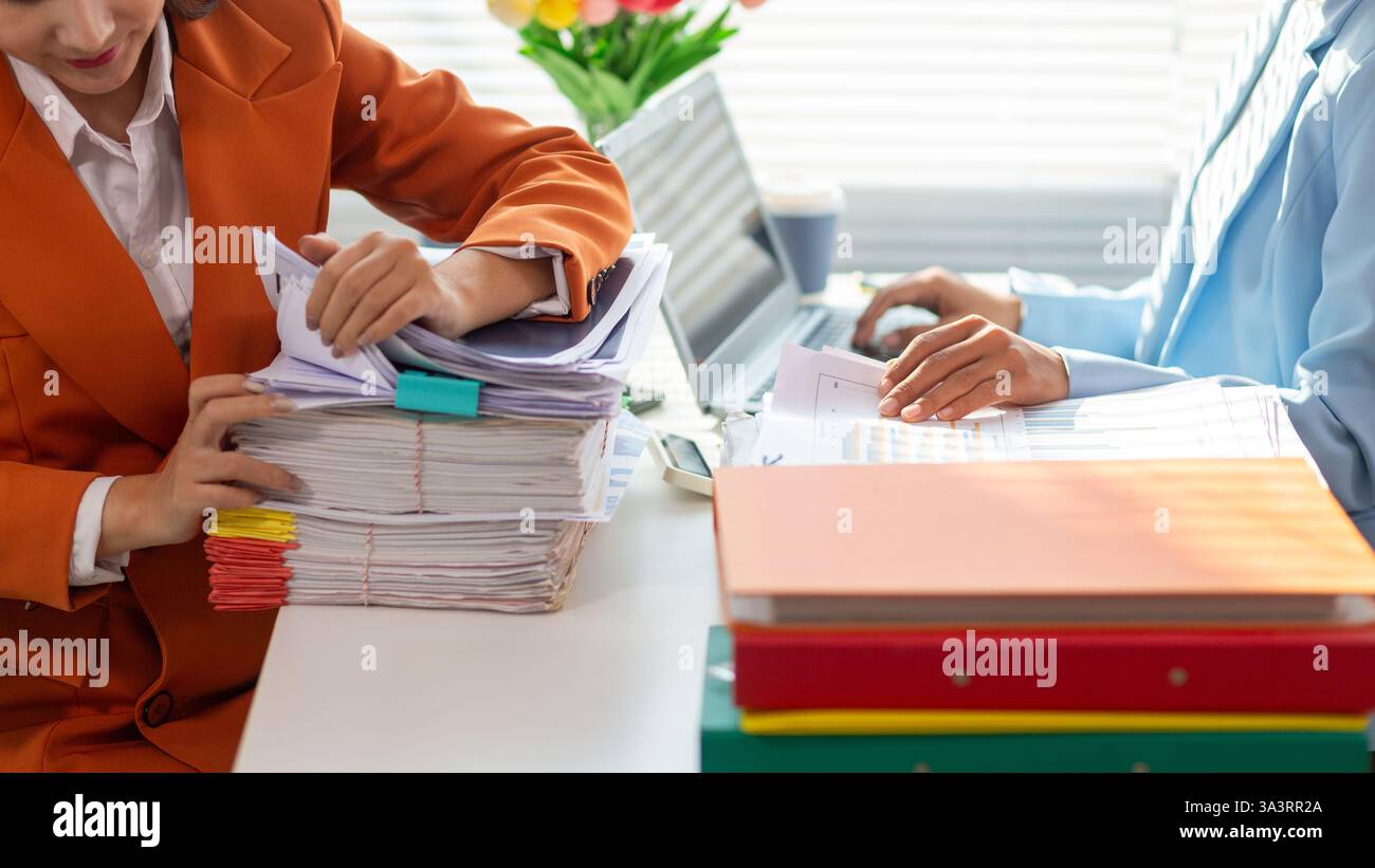 Two businesswomen are working together to search through important ...