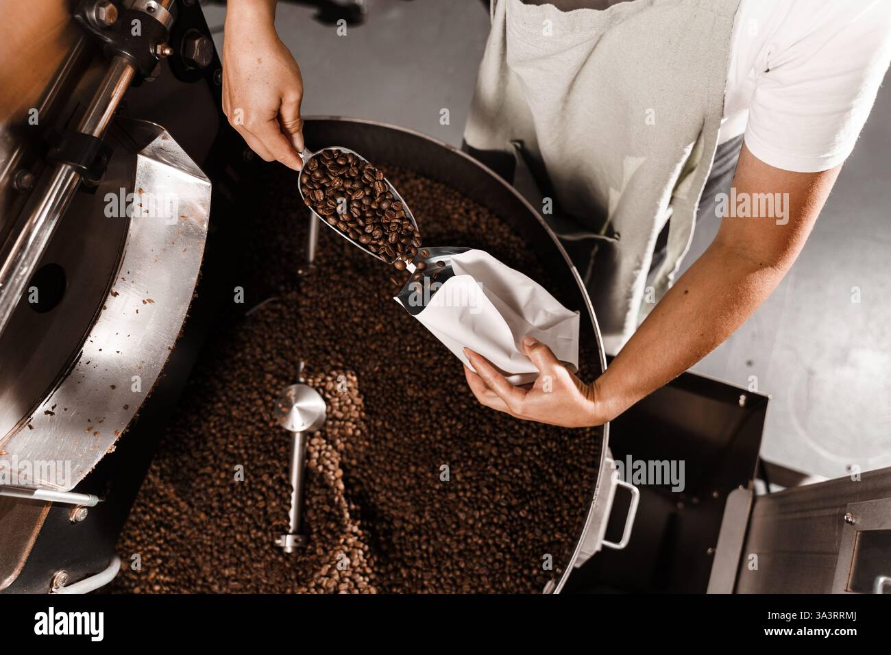 Packing roasted coffee beans into a craft bag. Pouring fried coffee ...