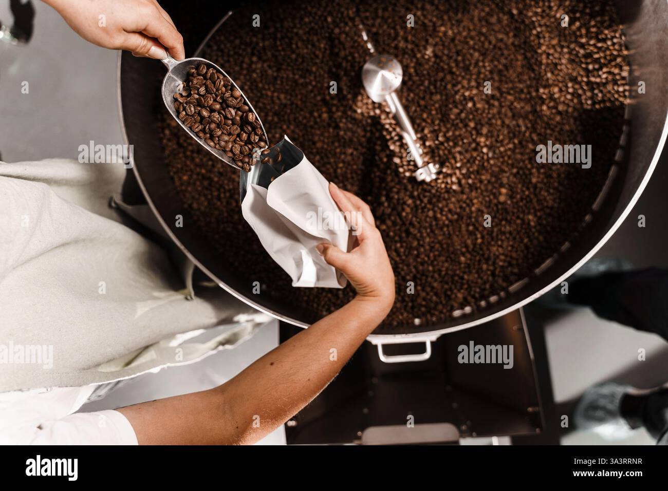 Packing roasted coffee beans into a craft bag. Pouring fried coffee ...