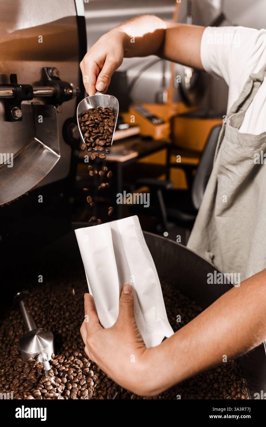 Packing roasted coffee beans into a craft bag. Pouring fried coffee ...