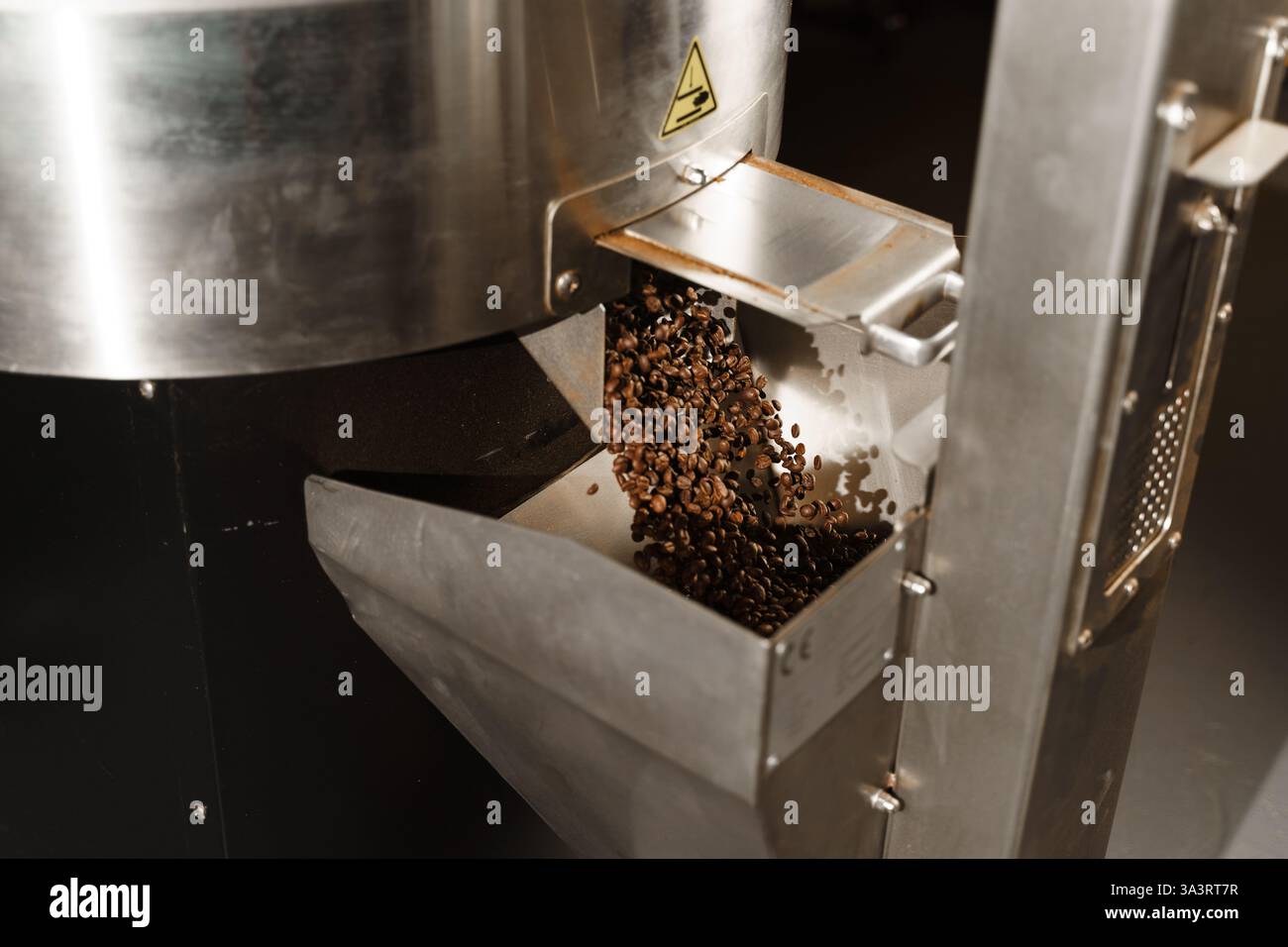 Coffee roasting process in the facility. Pouring freshly roasted coffee ...