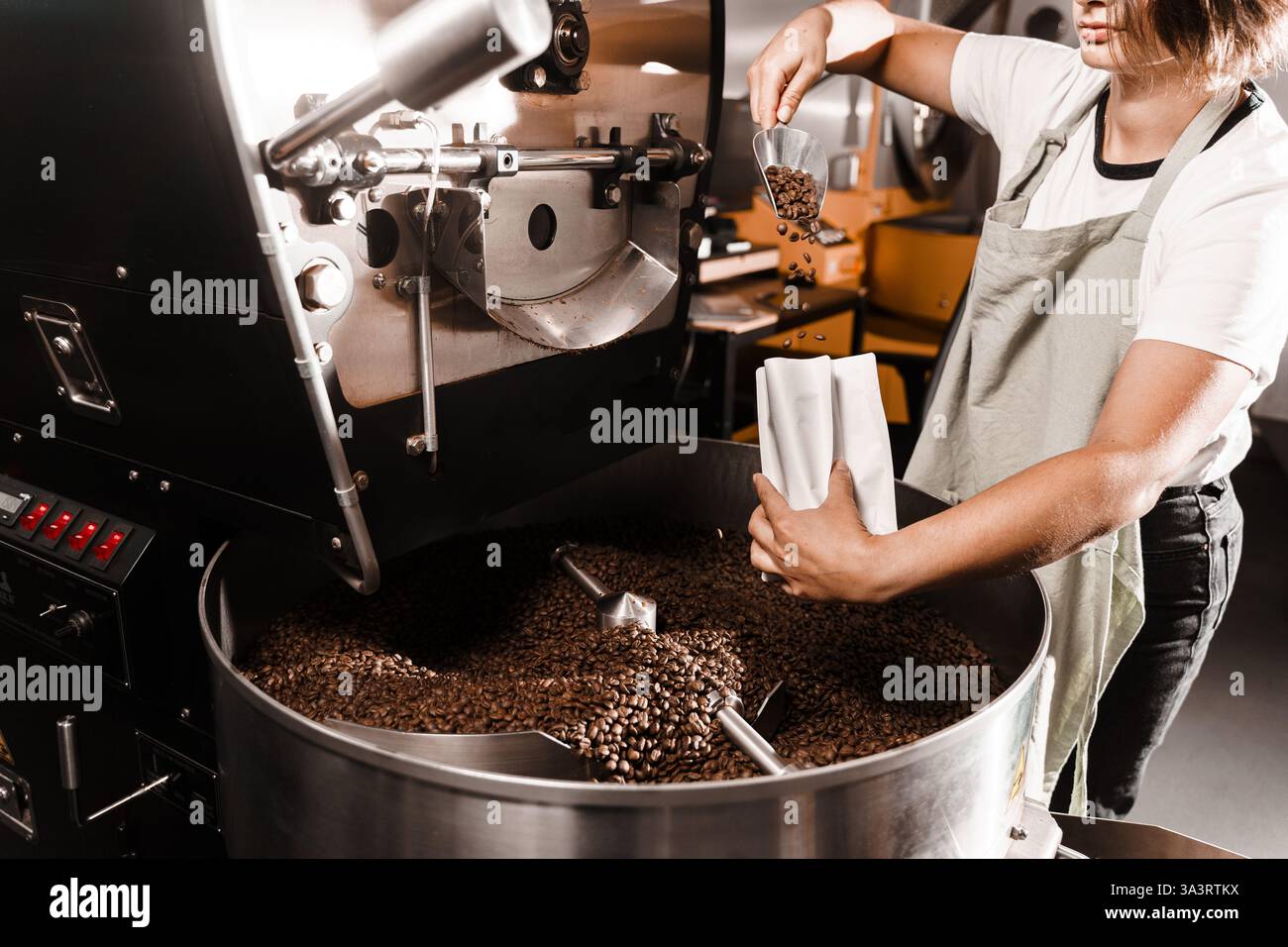 Pouring fried coffee grains in packaging bag in the facility. Packing ...
