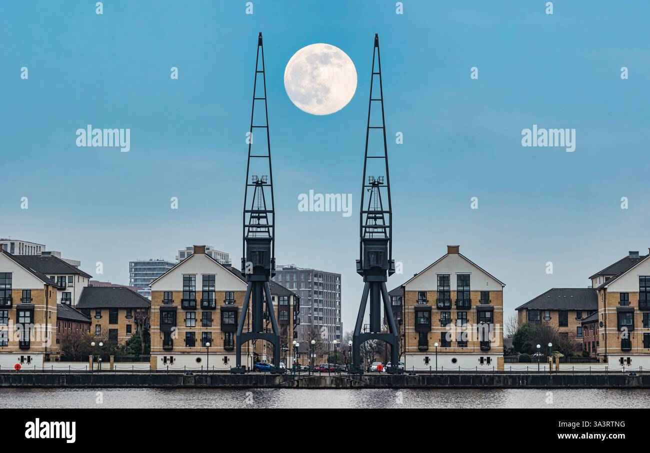 Full moon between disused cranes, Royal Victoria Dock on Thames River ...