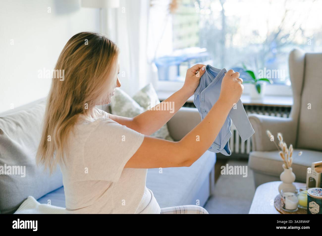 Young beautiful woman in pajamas is packing bag of baby things for the ...