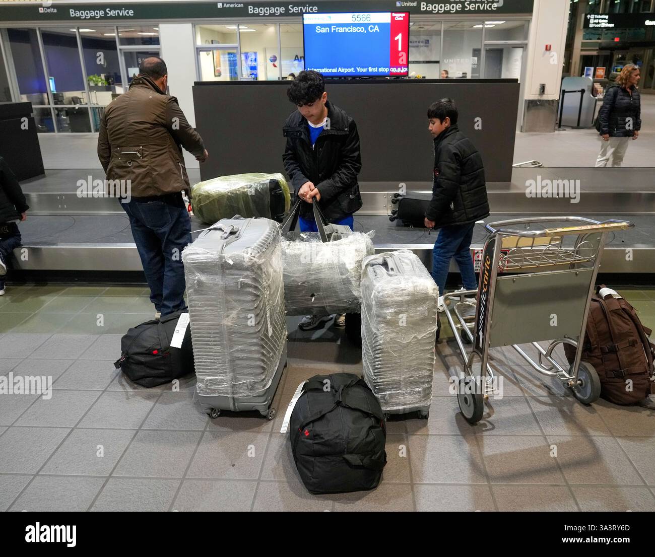 Mohammad Seyar Osmani, center, places a bag on a luggage cart, as he ...