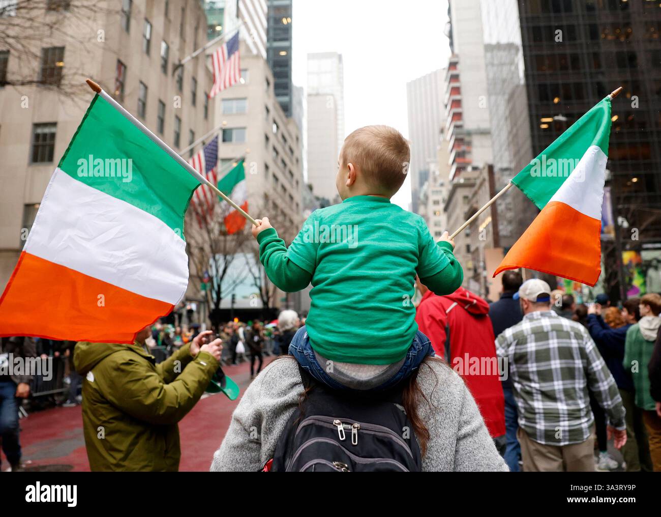 A child holds flags while sitting on the shoulders of an adult at the ...