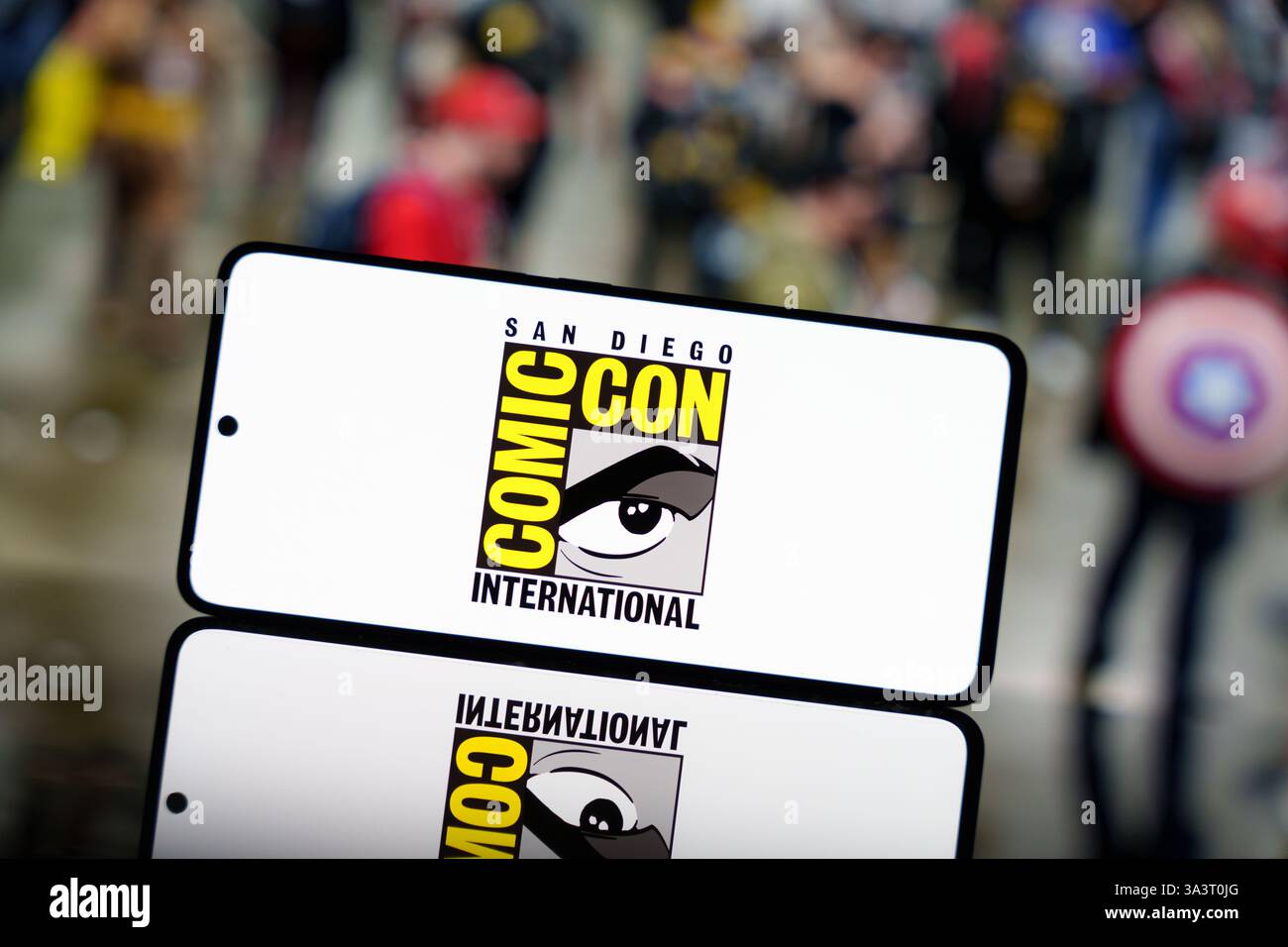 Smartphone displaying San Diego Comic-Con logo with blurred crowd of ...