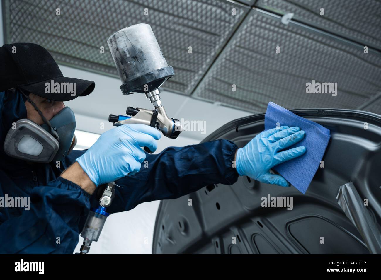 Car painter is painting automobile. Mechanic from vehicle maintenance ...