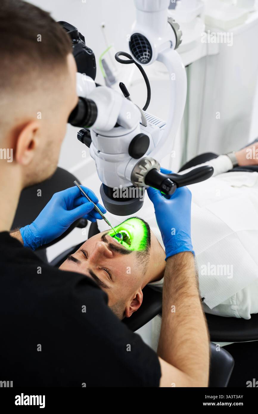 Surgical microscope examination procedure. Dentist is looking on teeth ...
