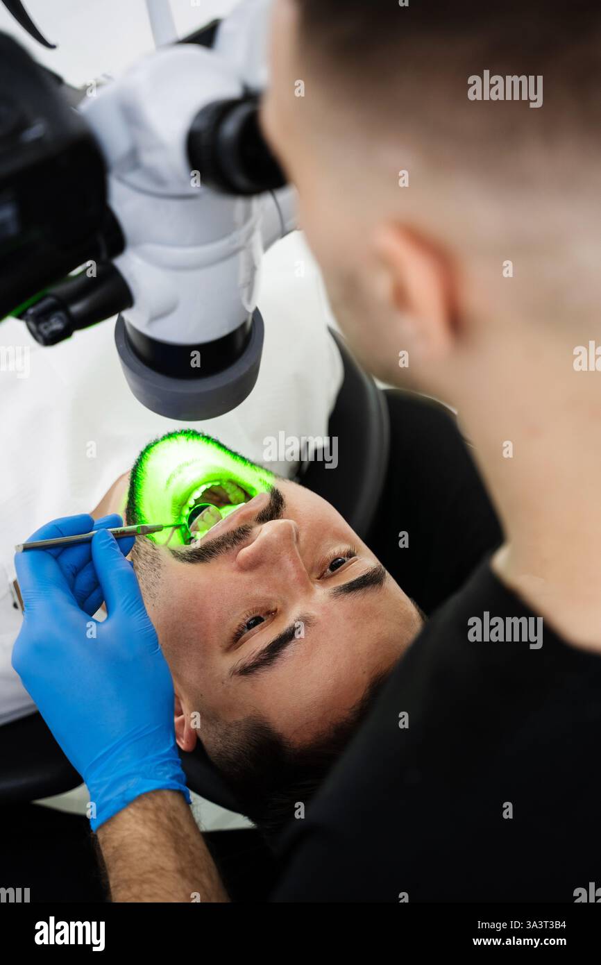 Surgical microscope examination procedure. Dentist is looking on teeth ...
