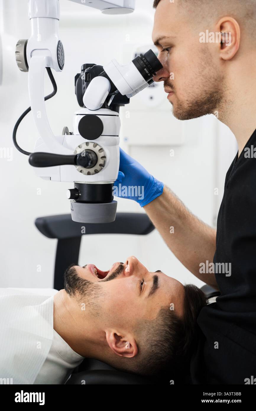 Surgical microscope examination procedure. Dentist is looking on teeth ...