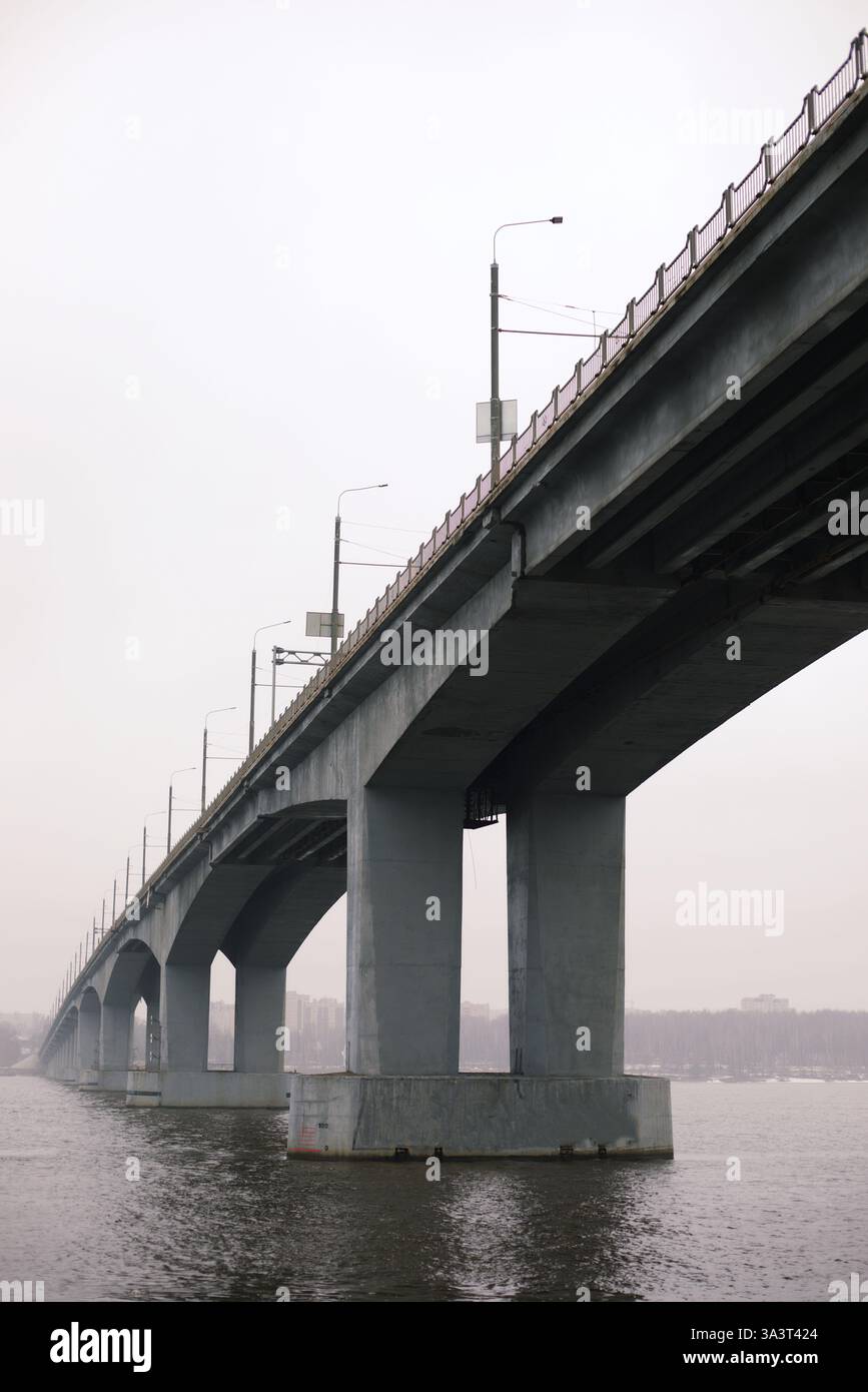 Large concrete bridge spanning a wide river on an overcast day. The ...
