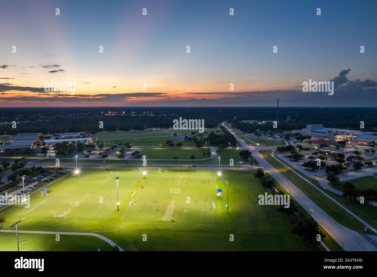 Public sports stadium with young people playing football game at sunset ...