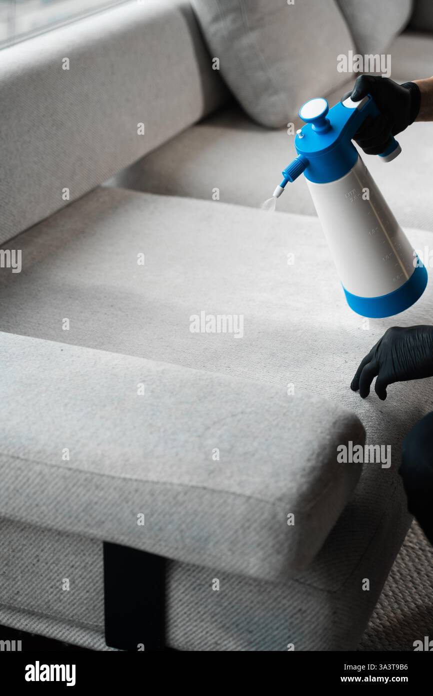 Spraying detergent to wash off stains from sofa. Cleaning furniture at ...