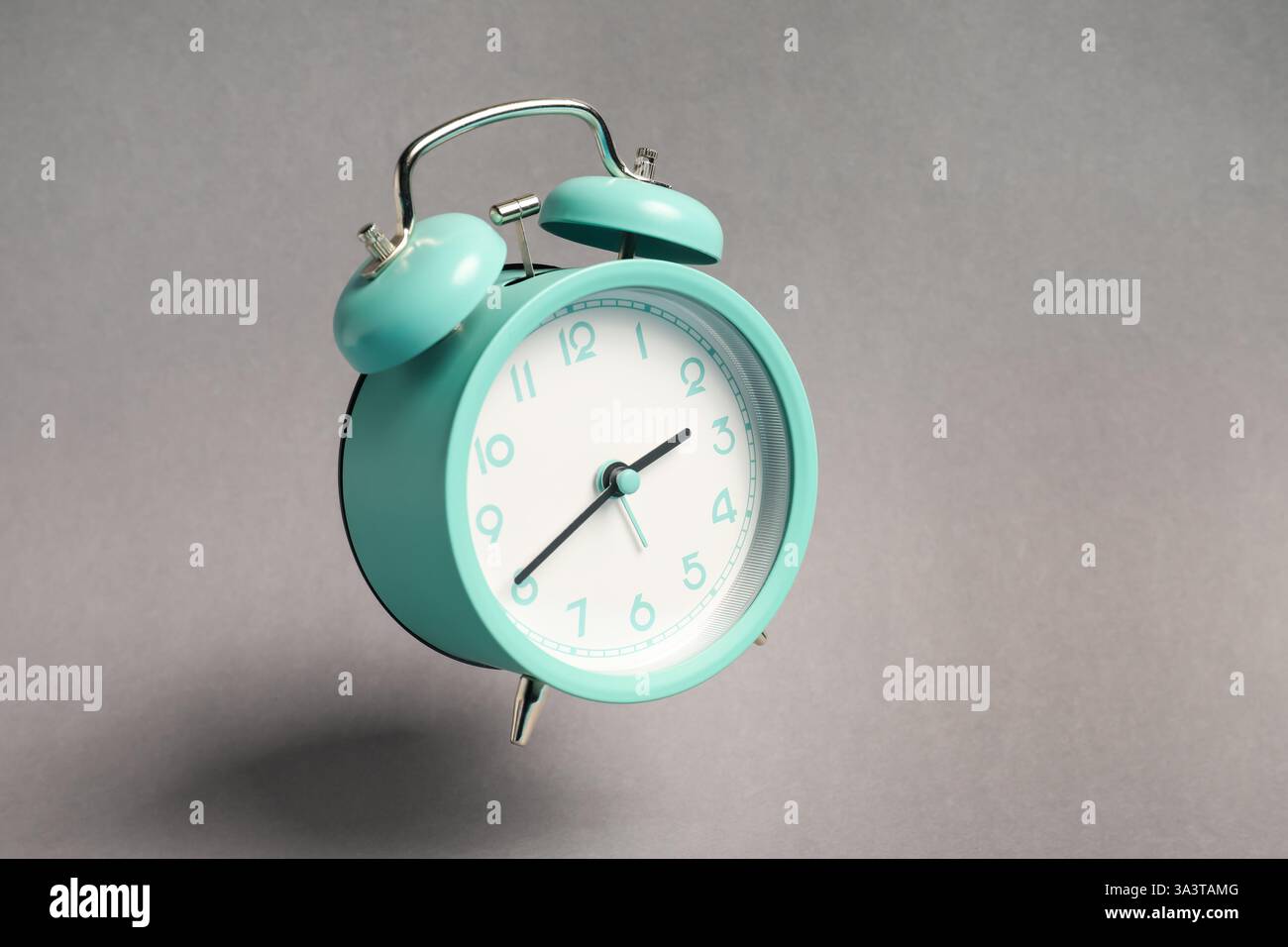 Turquoise alarm clock in air on light grey background Stock Photo - Alamy