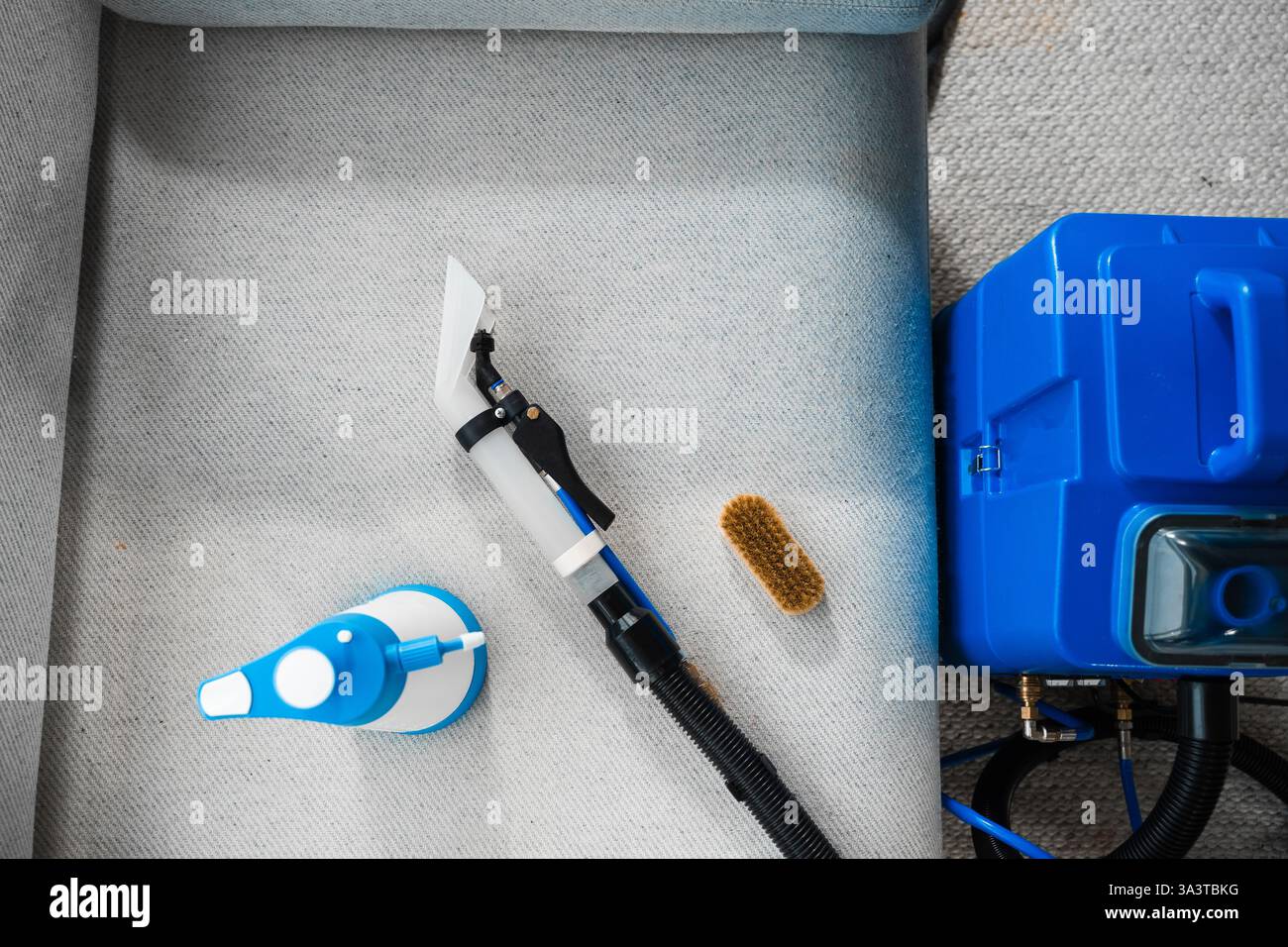 Cleaning equipment to dry cleaning gray sofa at home. Using extractor ...