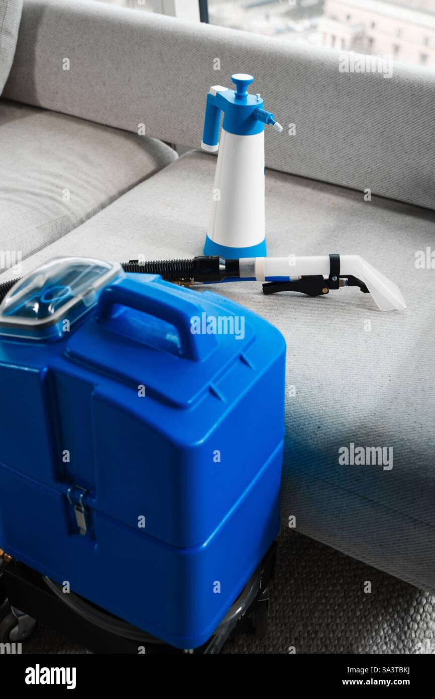 Cleaning equipment to dry cleaning gray sofa at home. Using extractor ...