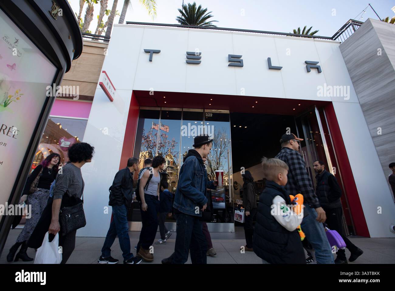 Glendale, California, USA - March 15, 2025: People walk past a Tesla ...
