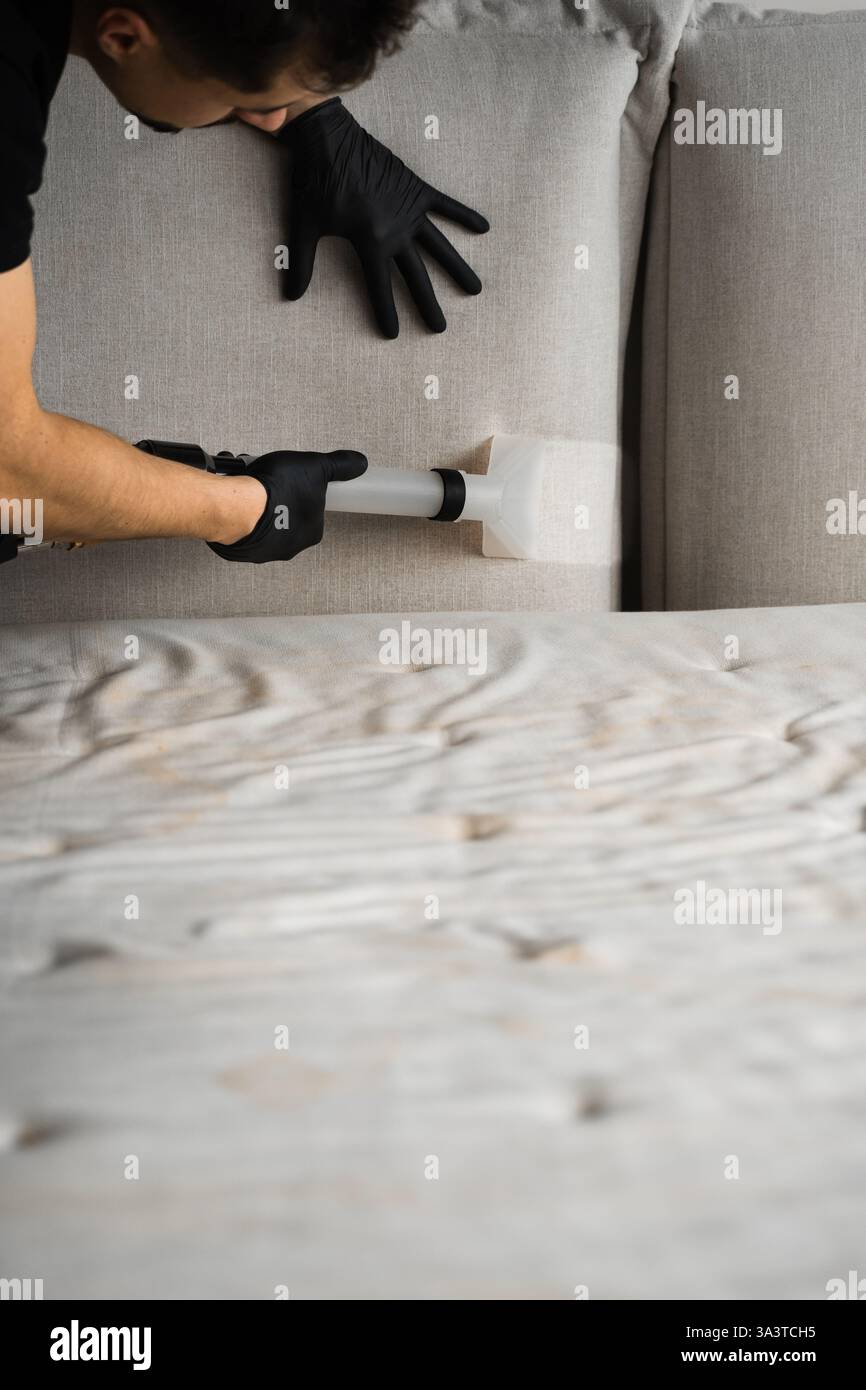 Cleaner is washing off couch from stains, dust and dirt using extractor ...