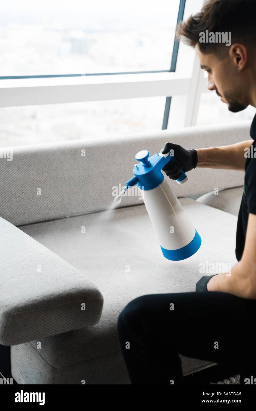 Cleaning furniture at home with spray detergent. Spraying detergent to ...