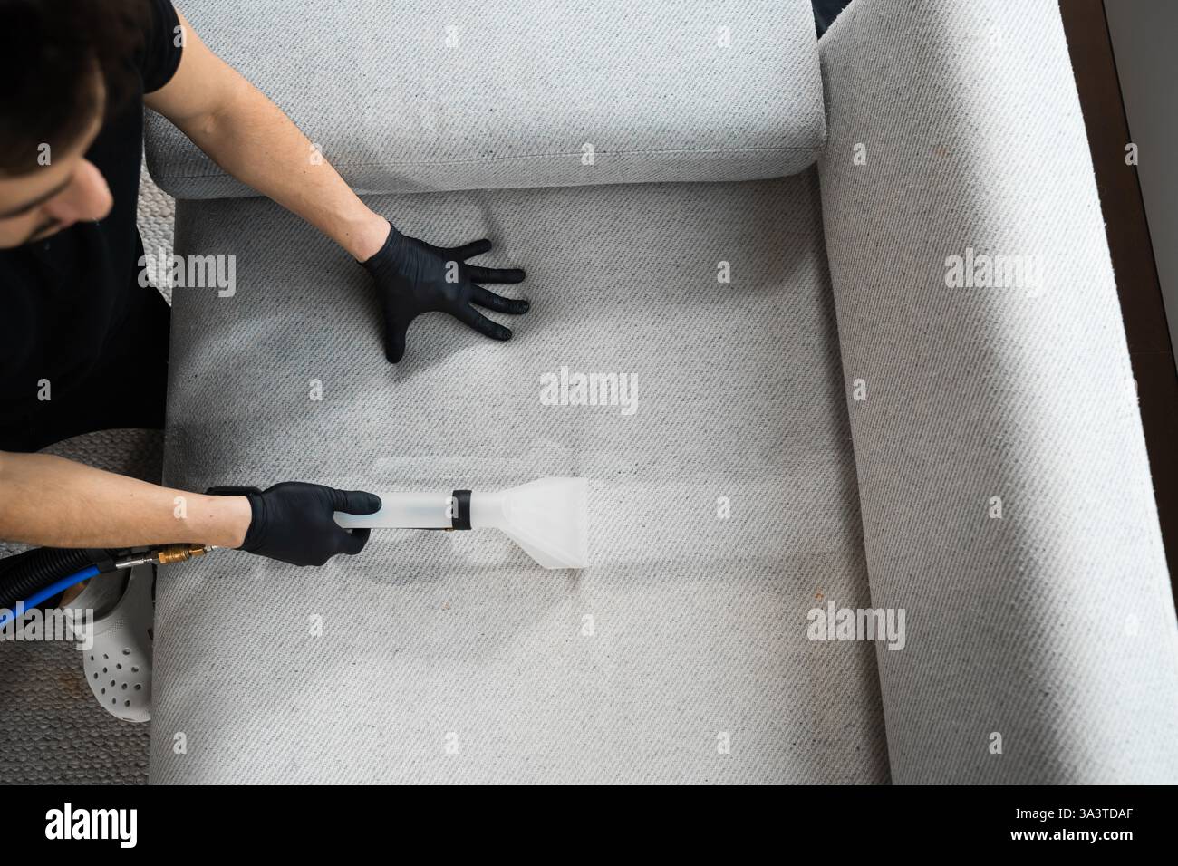 Cleaner is dry-cleaning sofa using extractor machine with detergent ...