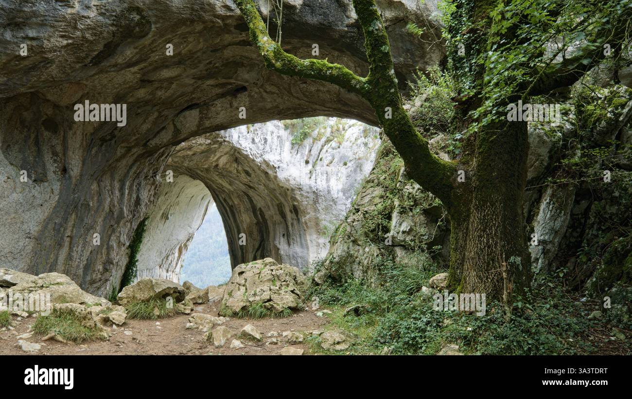 Scenic view of a natural stone arch cave surrounded by rugged rock ...
