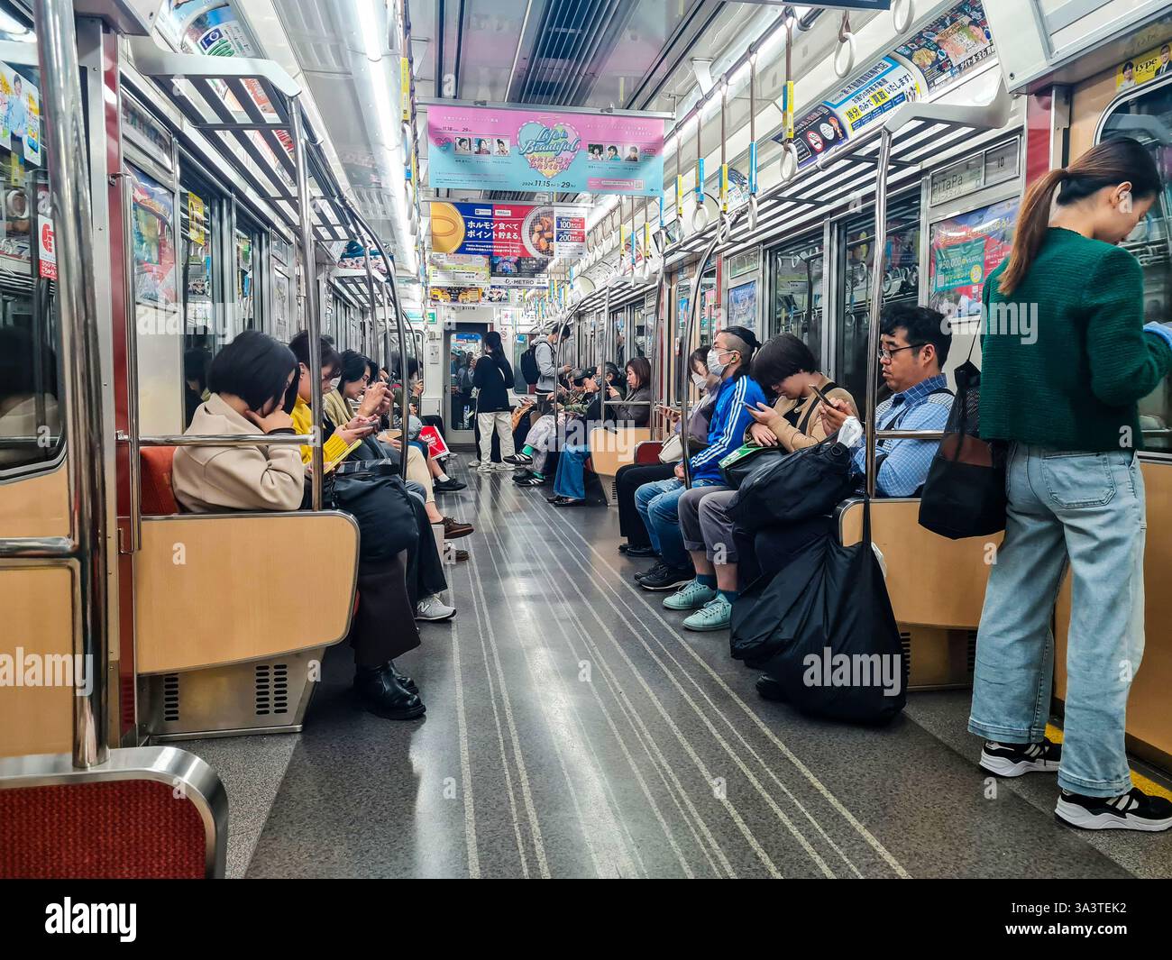 Inside a Japanese train with passengers seated and standing Stock Photo ...