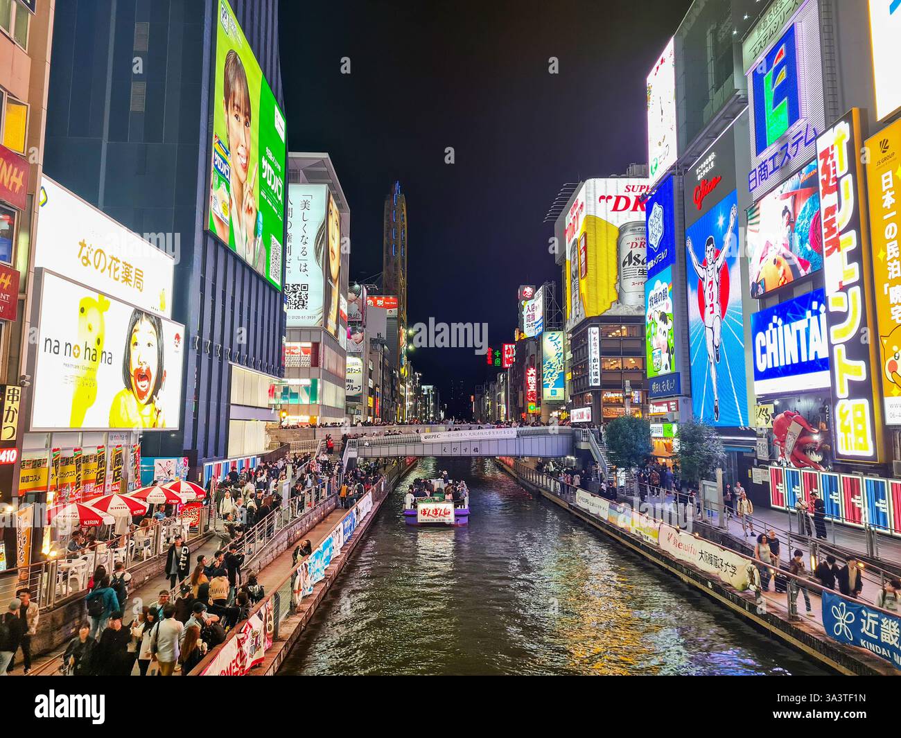 The Dotonbori river at night with lit up billboards and neon lights in ...