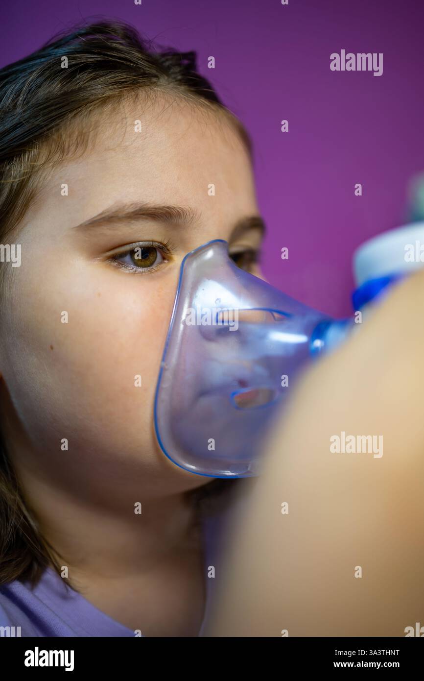 Child using a nebulizer for respiratory treatment at home during ...