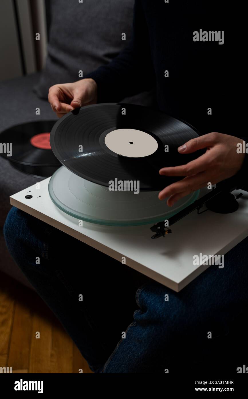 Musician puts on a vinyl record to play into turntable player ...