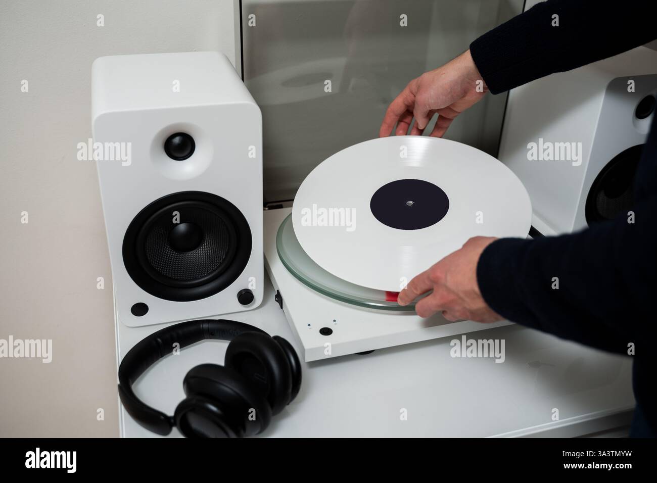 Musician places a white vinyl record into a turntable to enjoy ...