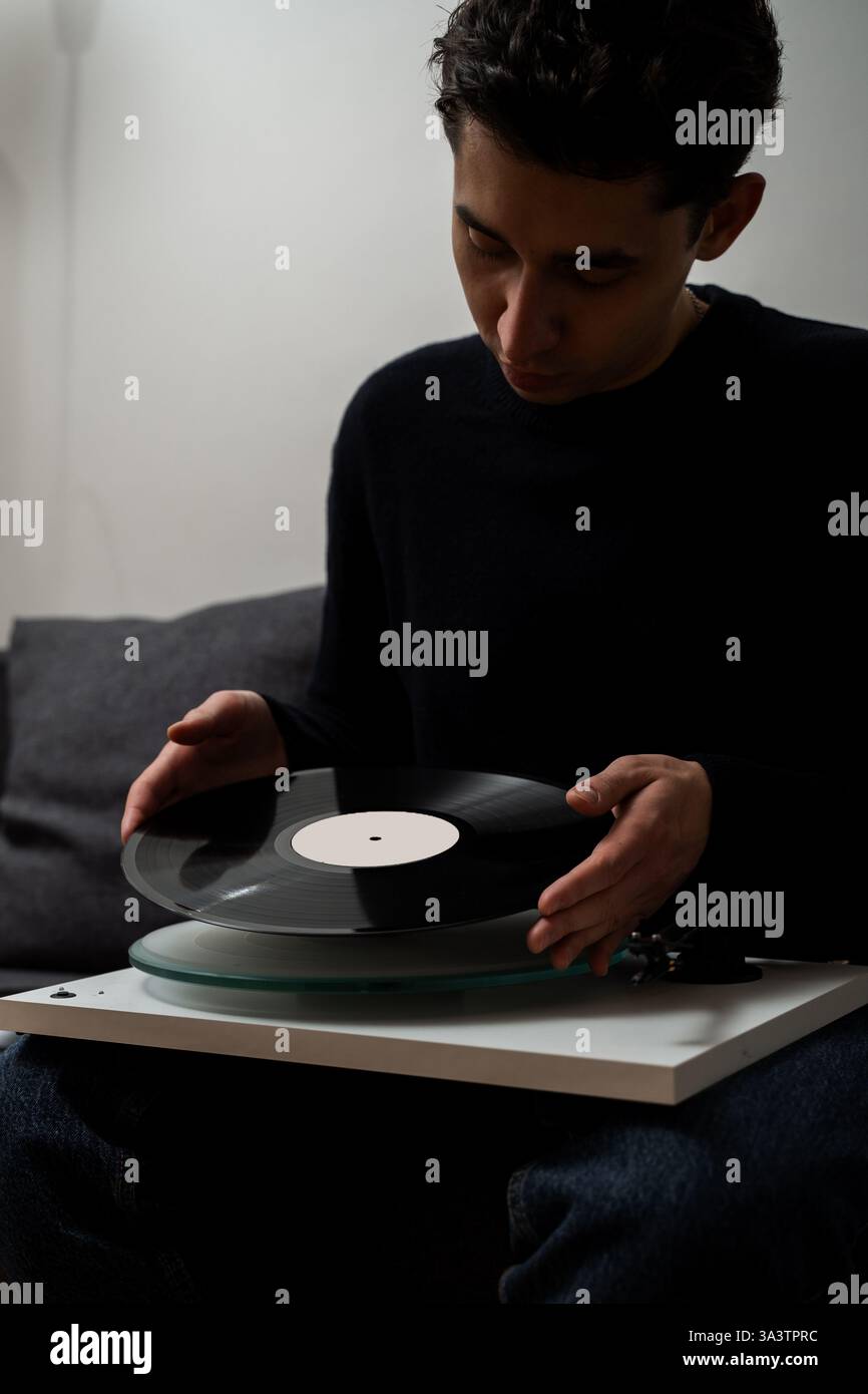 Musician puts on a vinyl record to play into turntable player ...