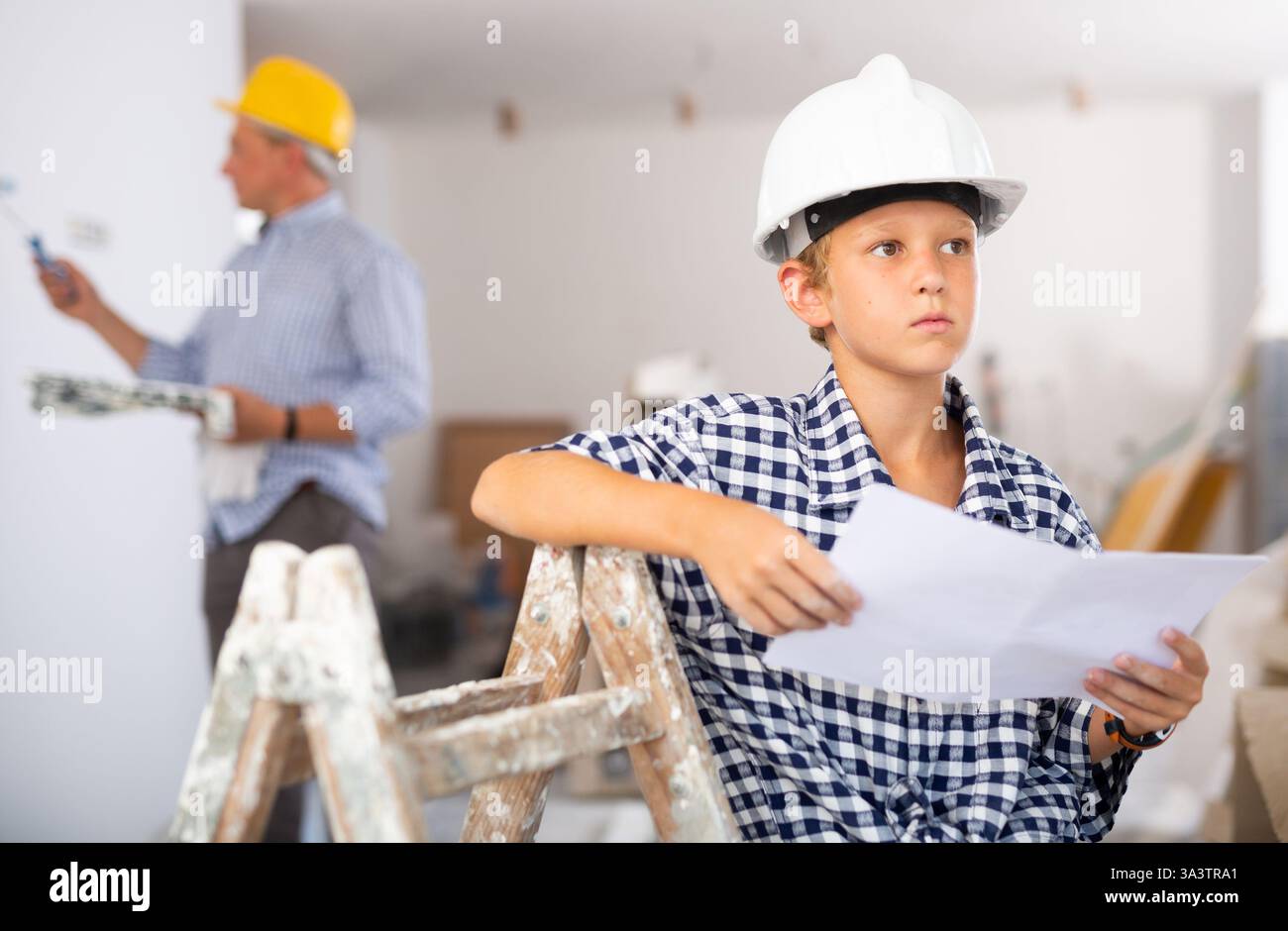Portrait of builder boy checking blueprints in room being renovated ...