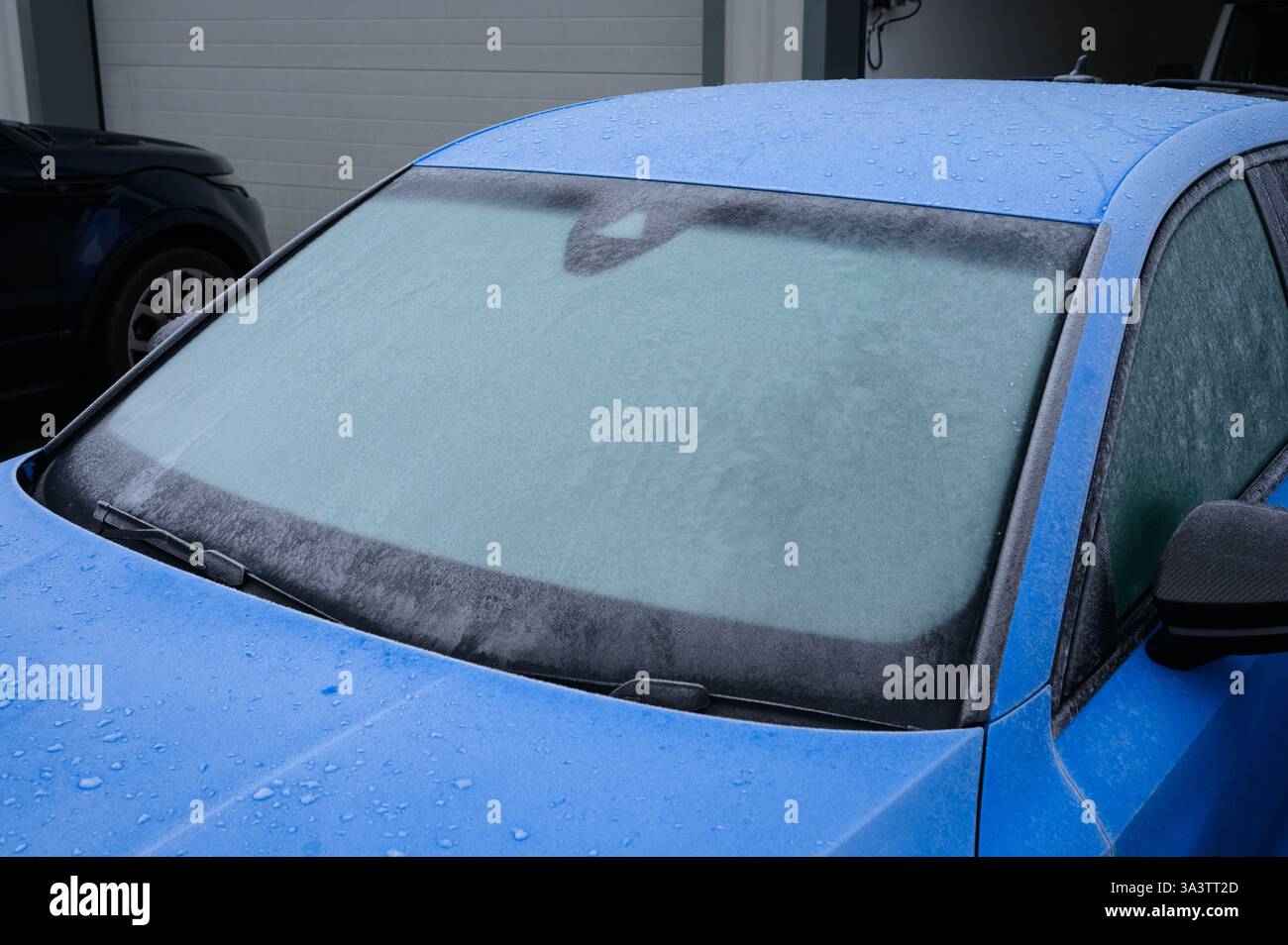 A blue car with a frosted windshield. The windshield is covered in ice ...