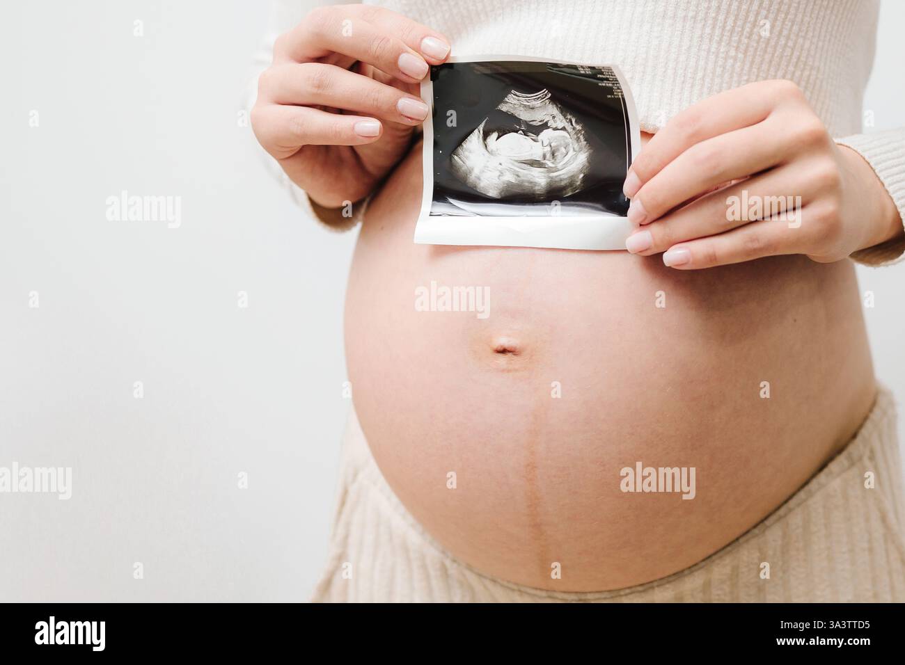 Pregnant holds sonogram picture of unborn baby inside her big belly ...
