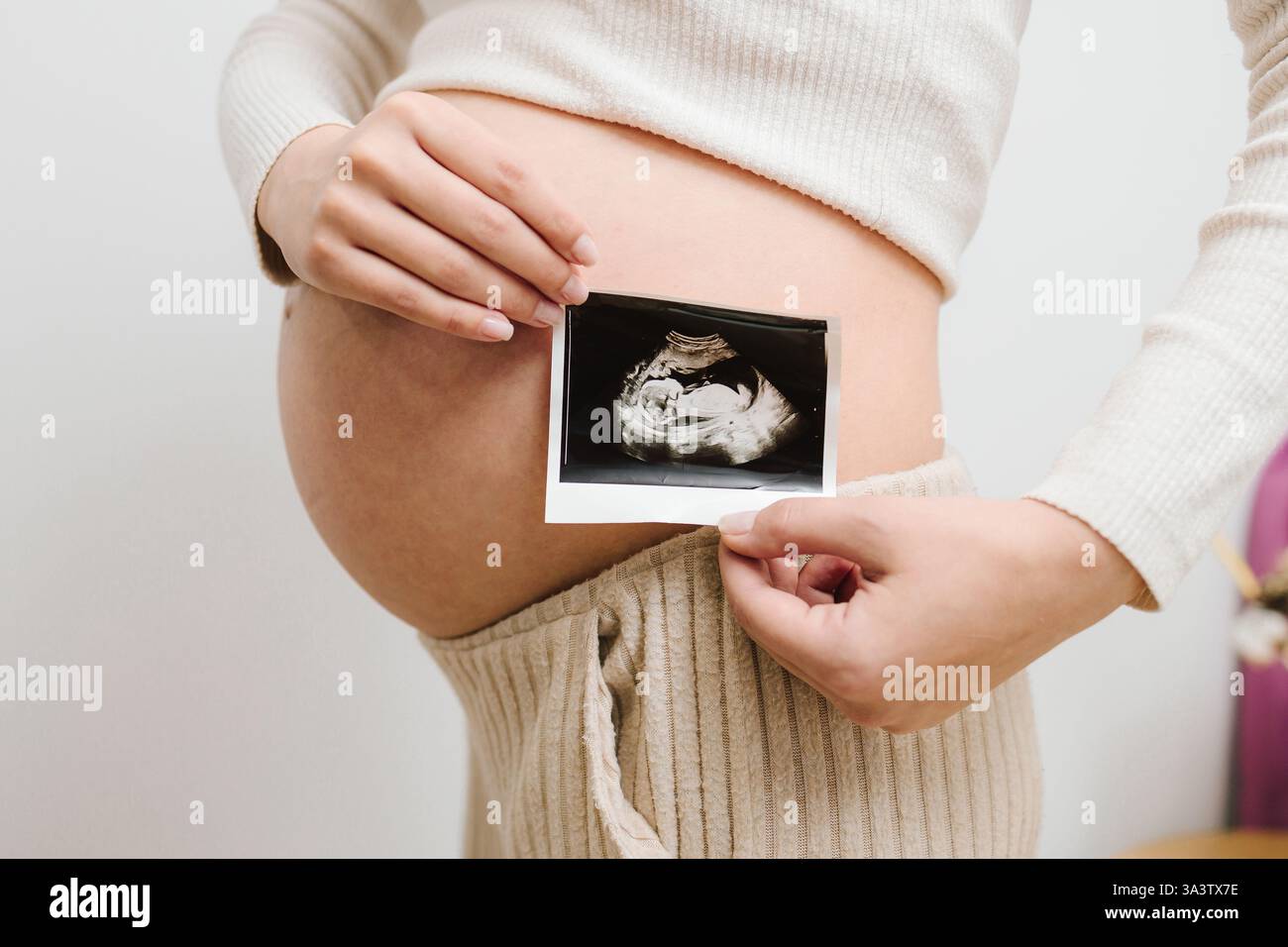 Pregnant holds sonogram picture of unborn baby inside her big belly ...