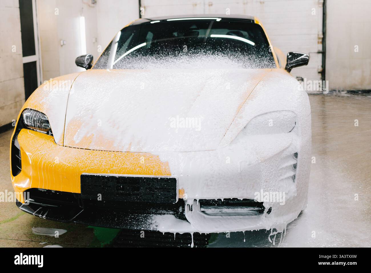 Application of soapy foam with a water gun for sports car cleaning at ...