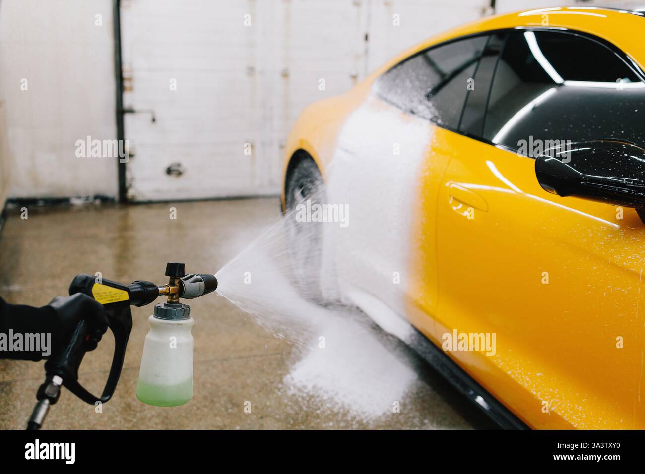 Application of soapy foam with a water gun for sports car cleaning at ...