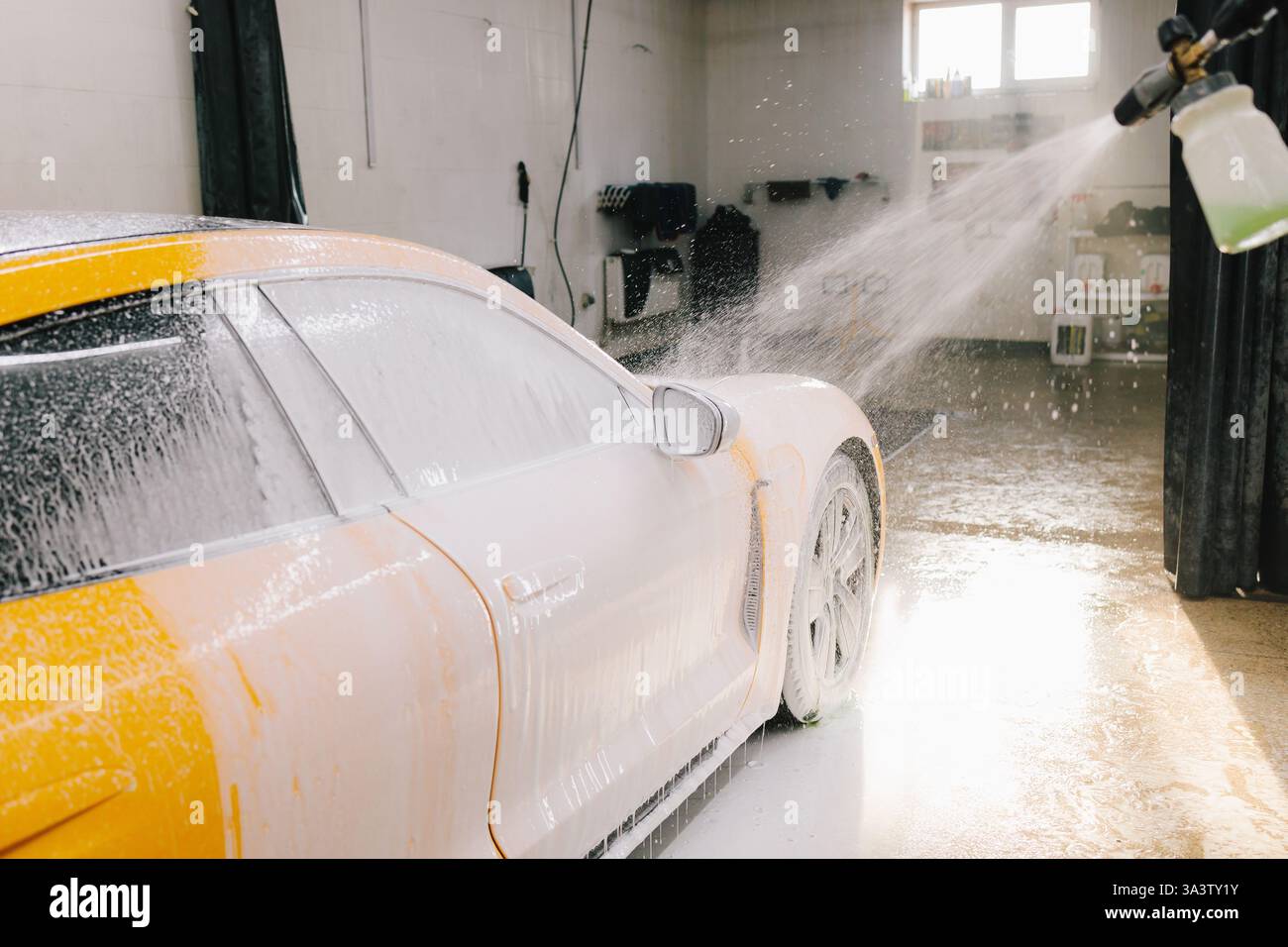 High-pressure water gun spraying soapy solution onto the vehicle's ...