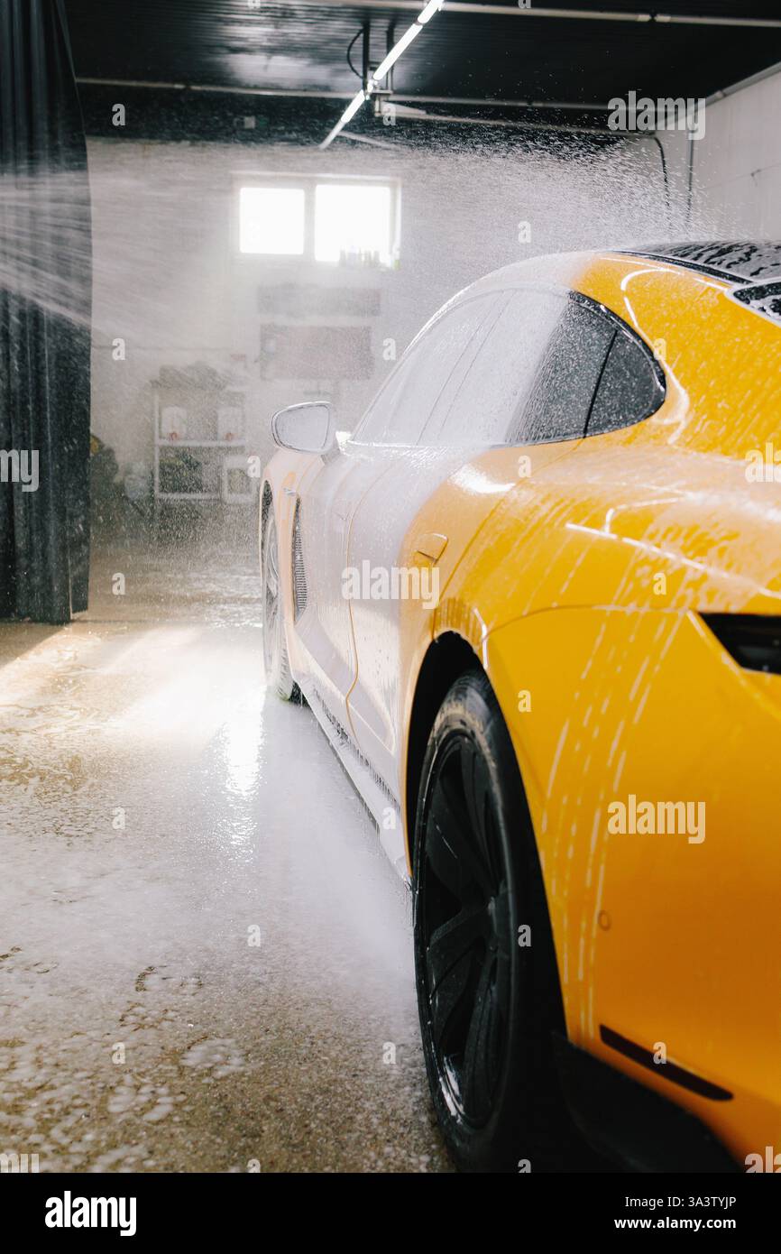 High-pressure water gun spraying soapy solution onto the vehicle's ...