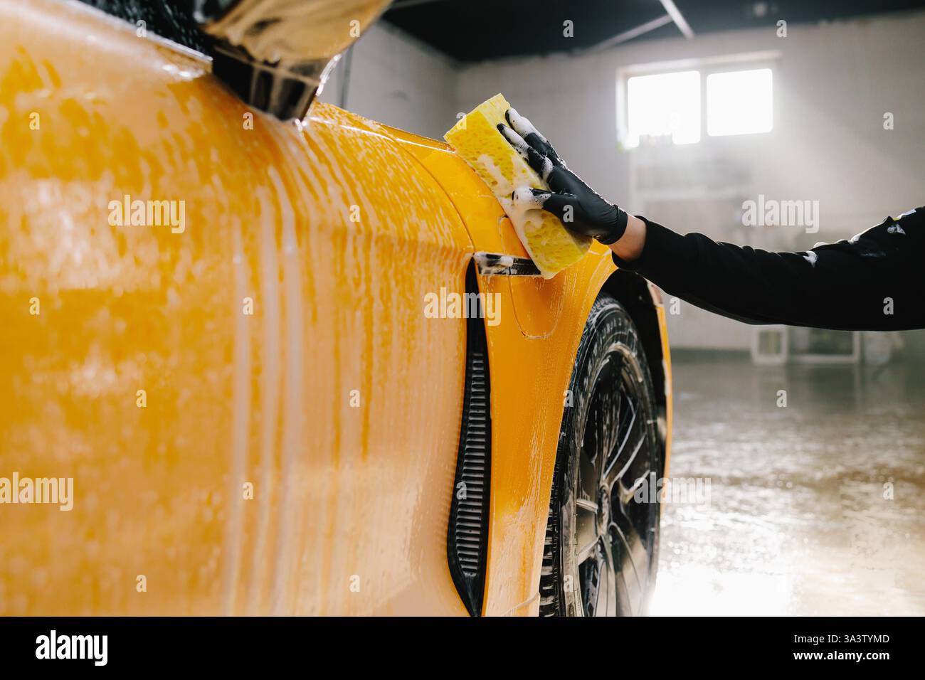 Hand cleaning of sports car using sponge and foam at the car wash ...