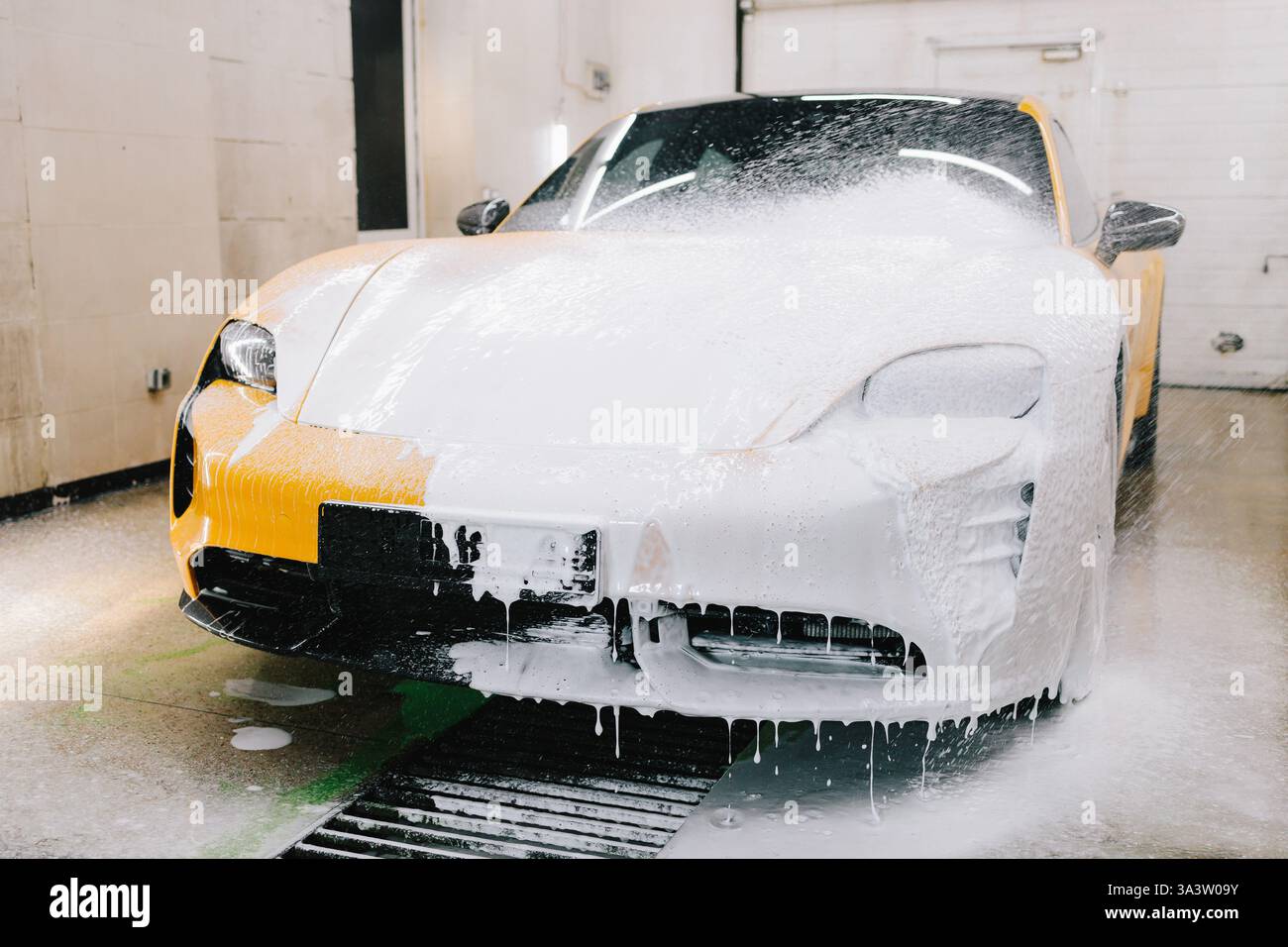 Application of soapy foam with a water gun for sports car cleaning at ...