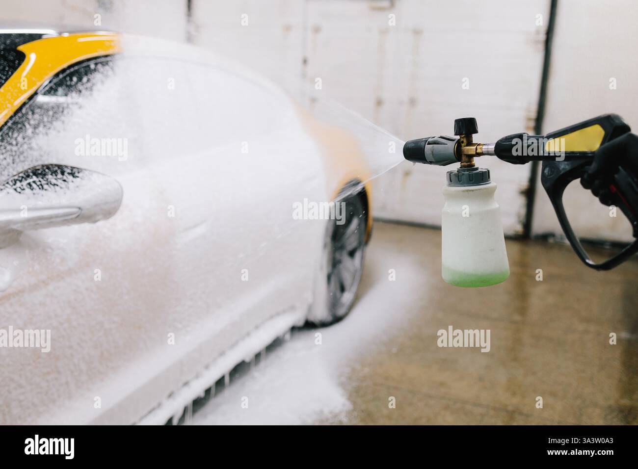 Application of soapy foam with a water gun for sports car cleaning at ...
