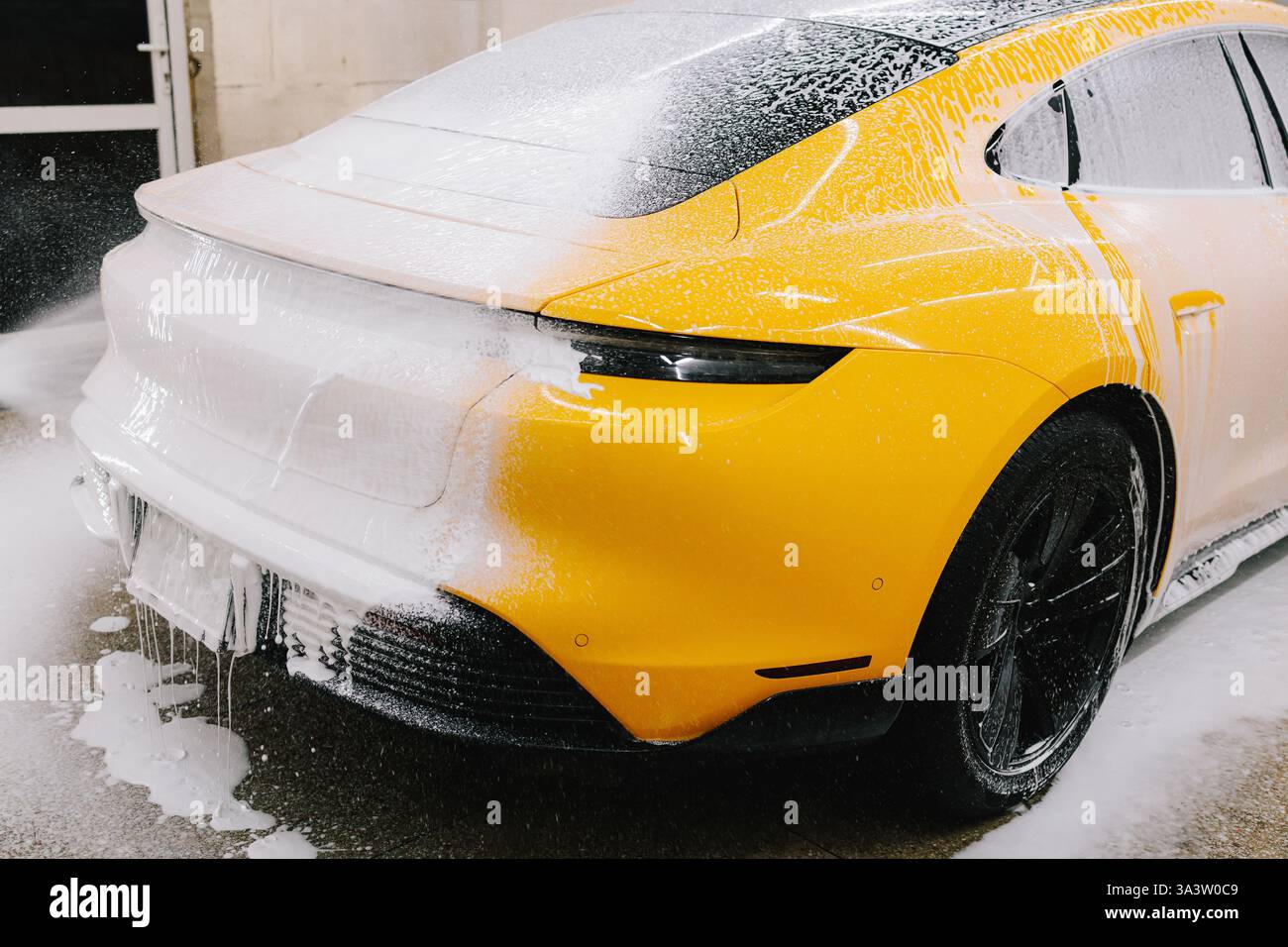 Application of soapy foam with a water gun for sports car cleaning at ...