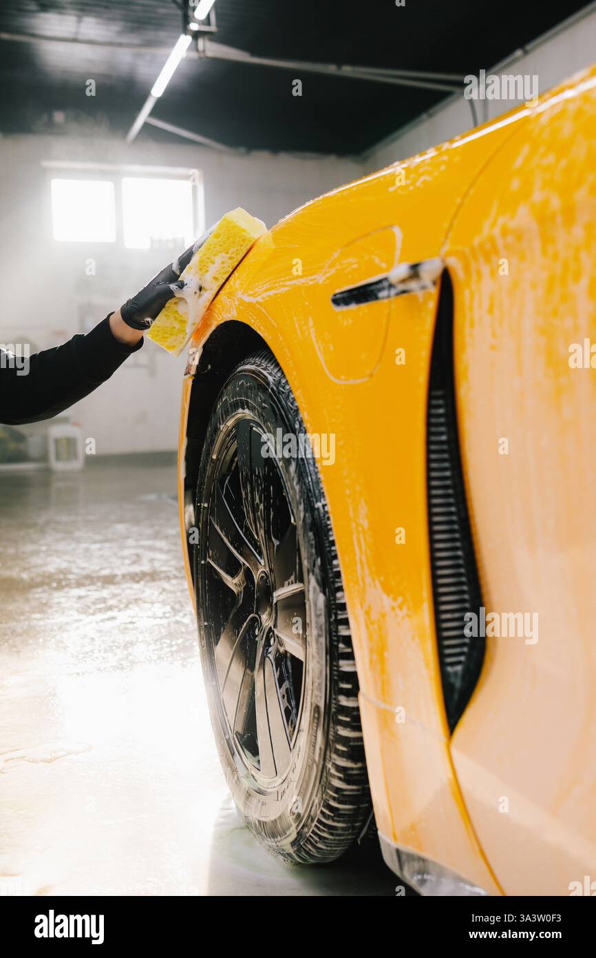 Hand cleaning of sports car using sponge and foam at the car wash ...