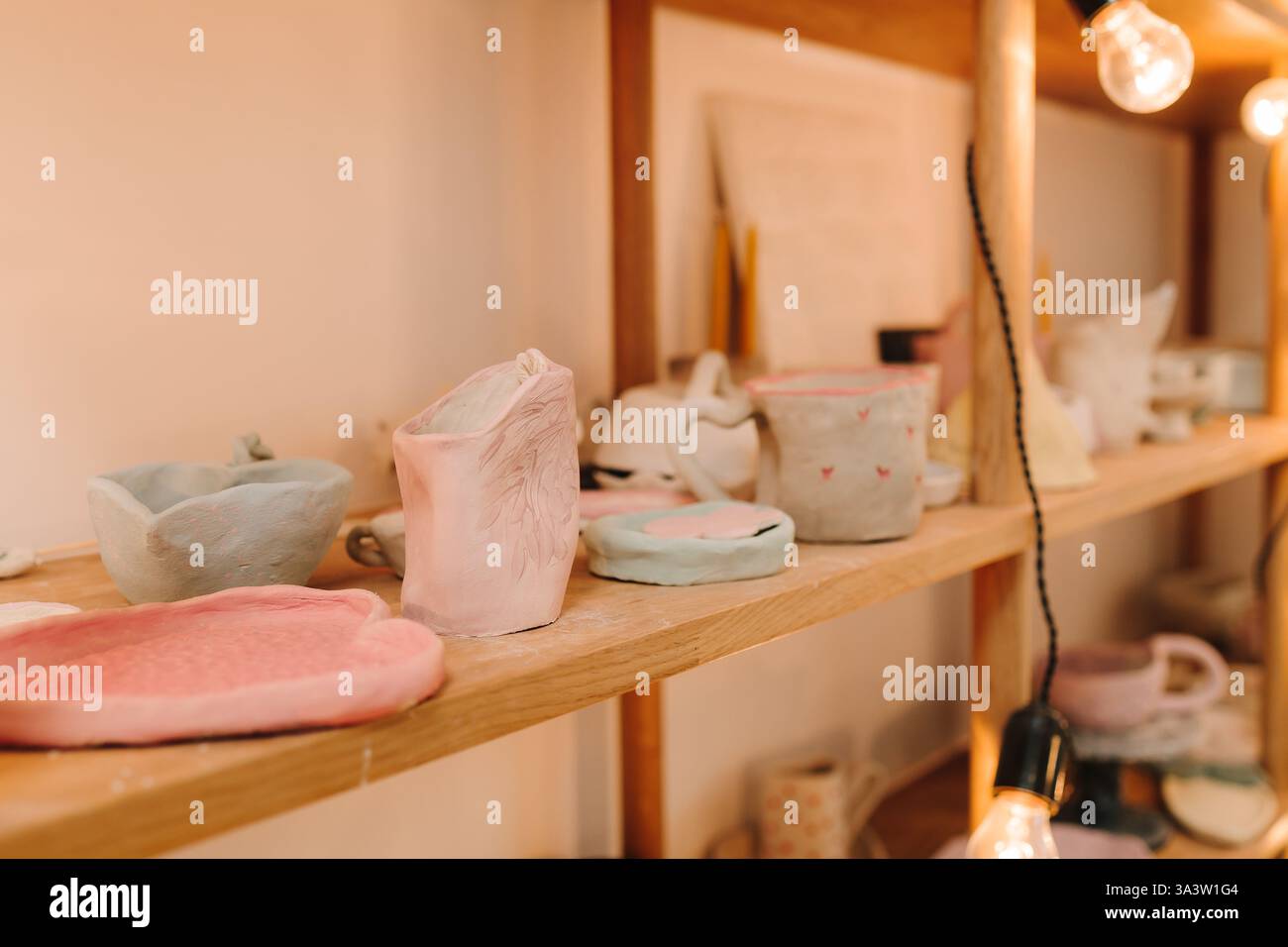 Shelf with handmade clay cups and plates in the pottery studio ...