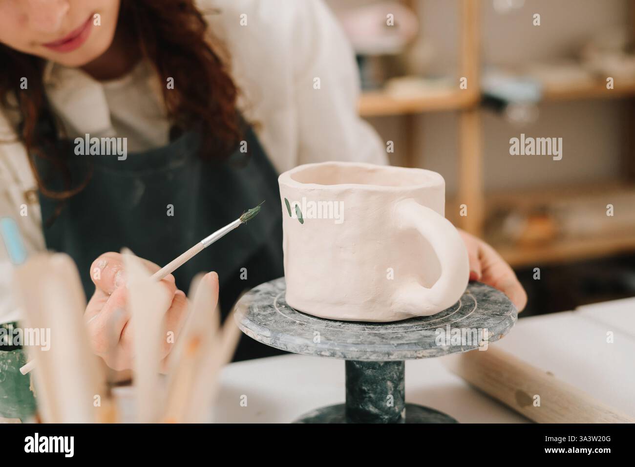 Artisan stamps decorative symbols on the dry clay of the cup. Process ...